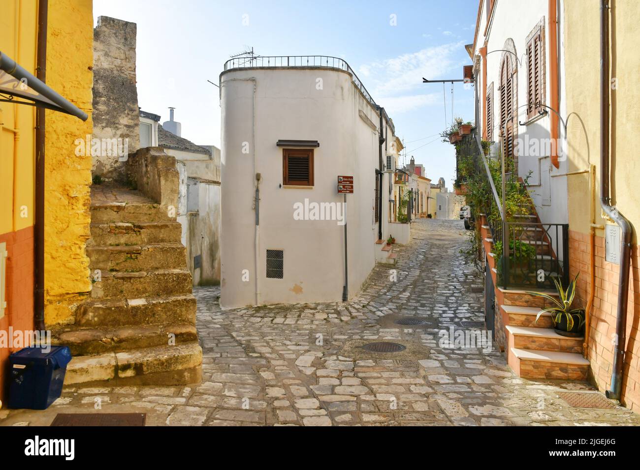 A narrow street between the old houses of Grottole, a village in the ...