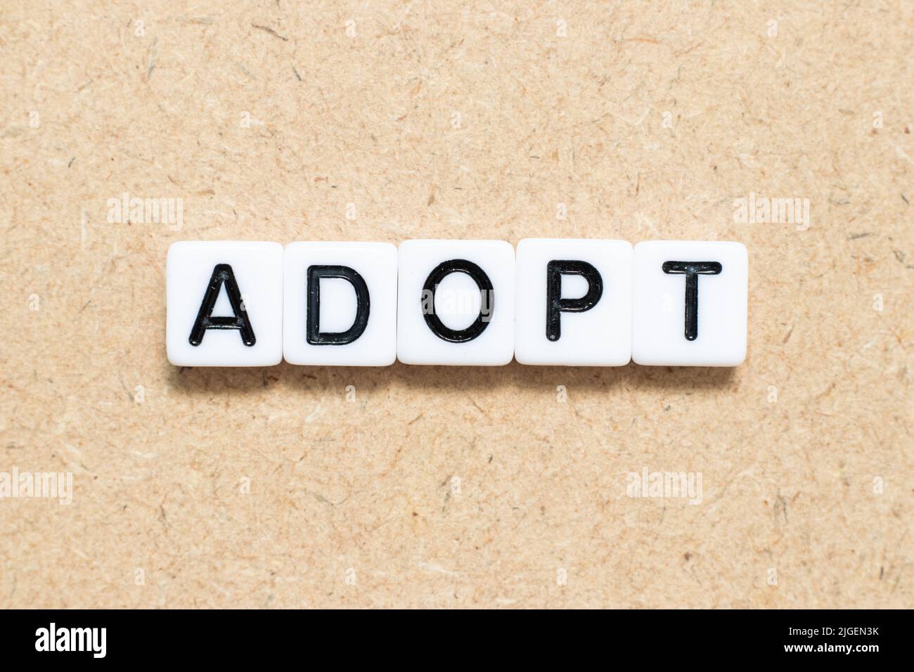 White tile alphabet letter with word adopt on wood background Stock ...