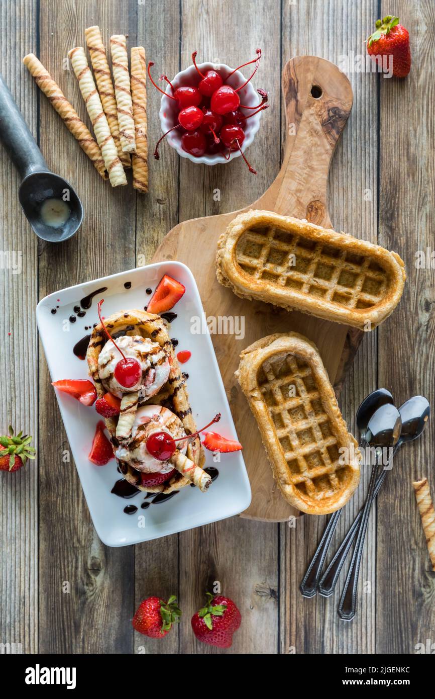 Top down view of a waffle boat sundae with all the fixings surrounding ...