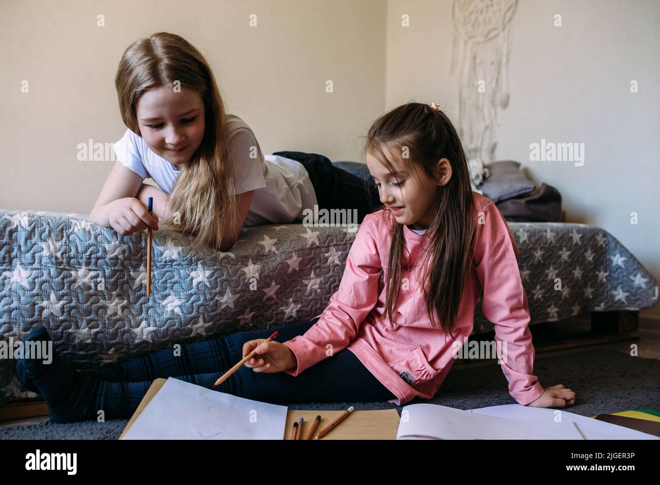 Two girls friends play at home, draw with pencils and felt-tip pens and ...