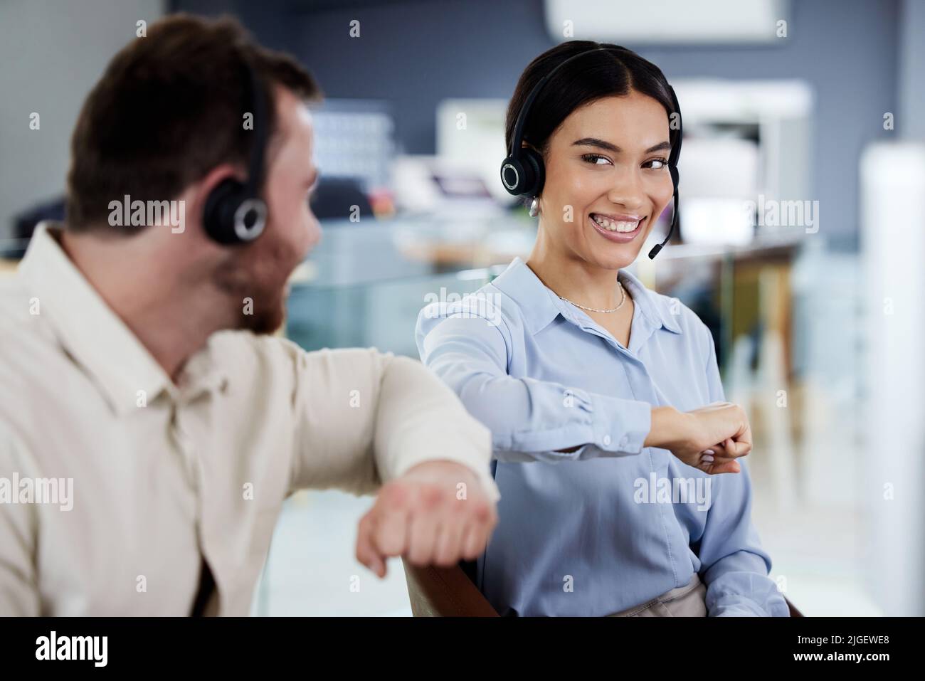 Greeting the Covid way. a young call centre agent sitting with a ...