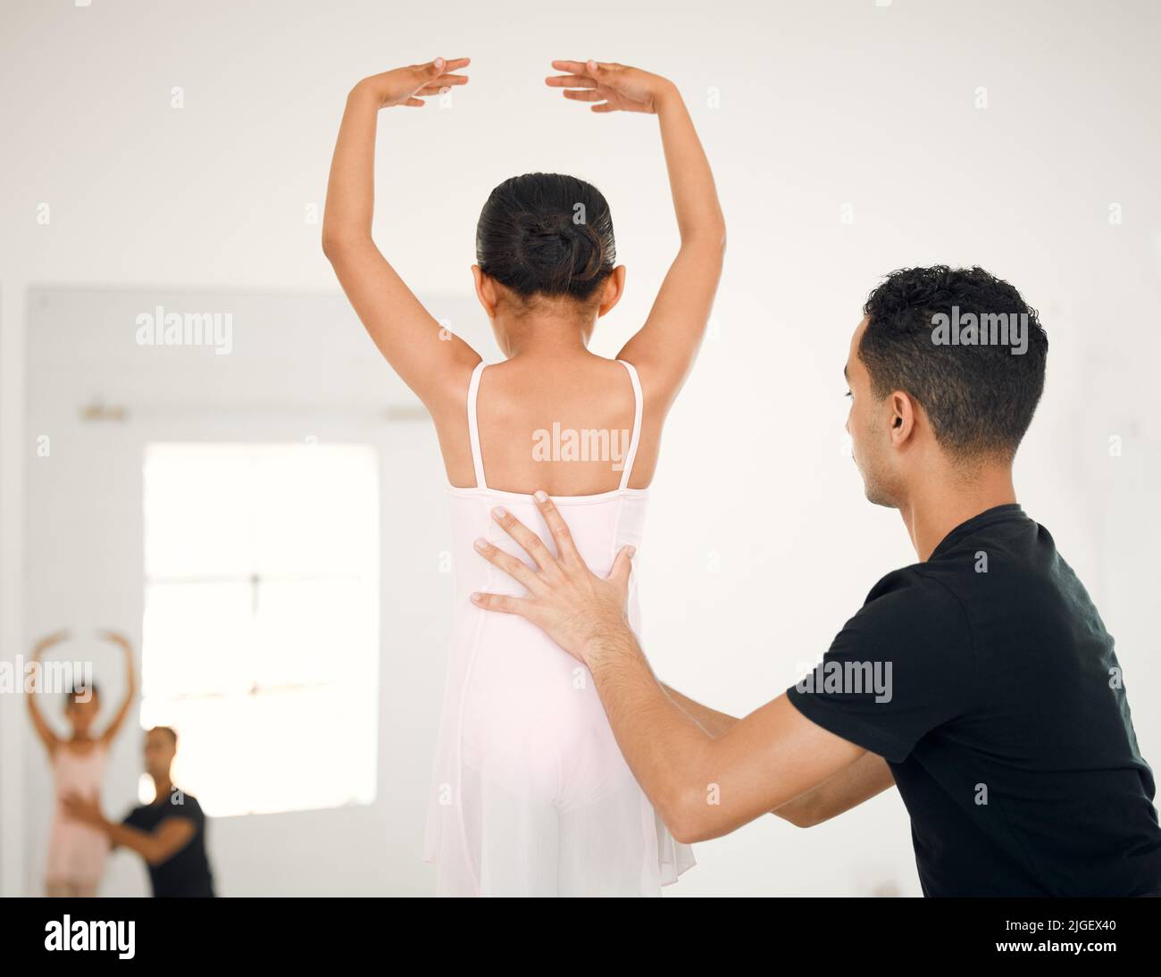 Stand up straight and lift your arms up. a ballet teacher assisting a ...