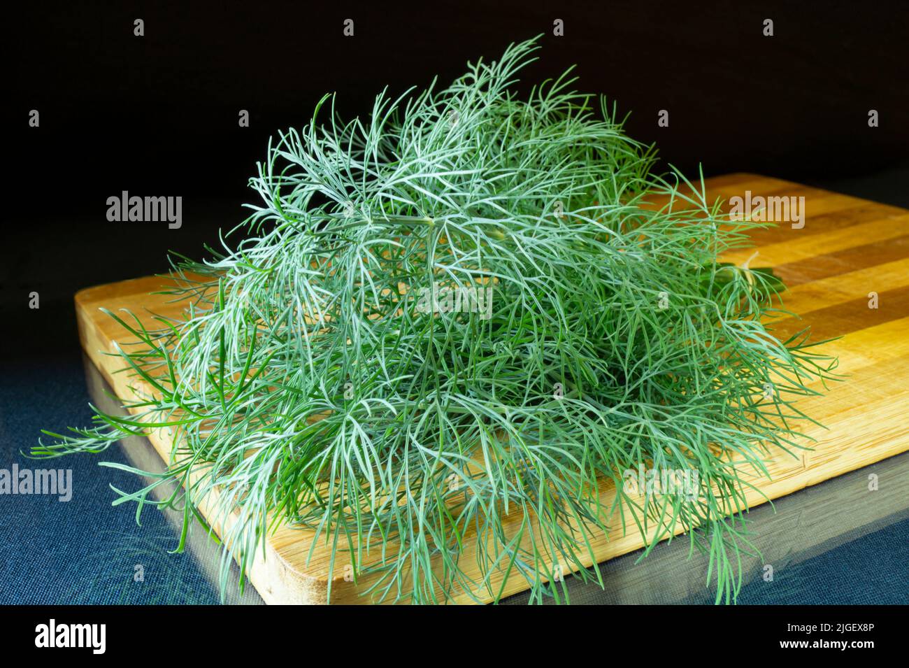 A bunch of dill on the table with a reflection. Green seasoning on a ...