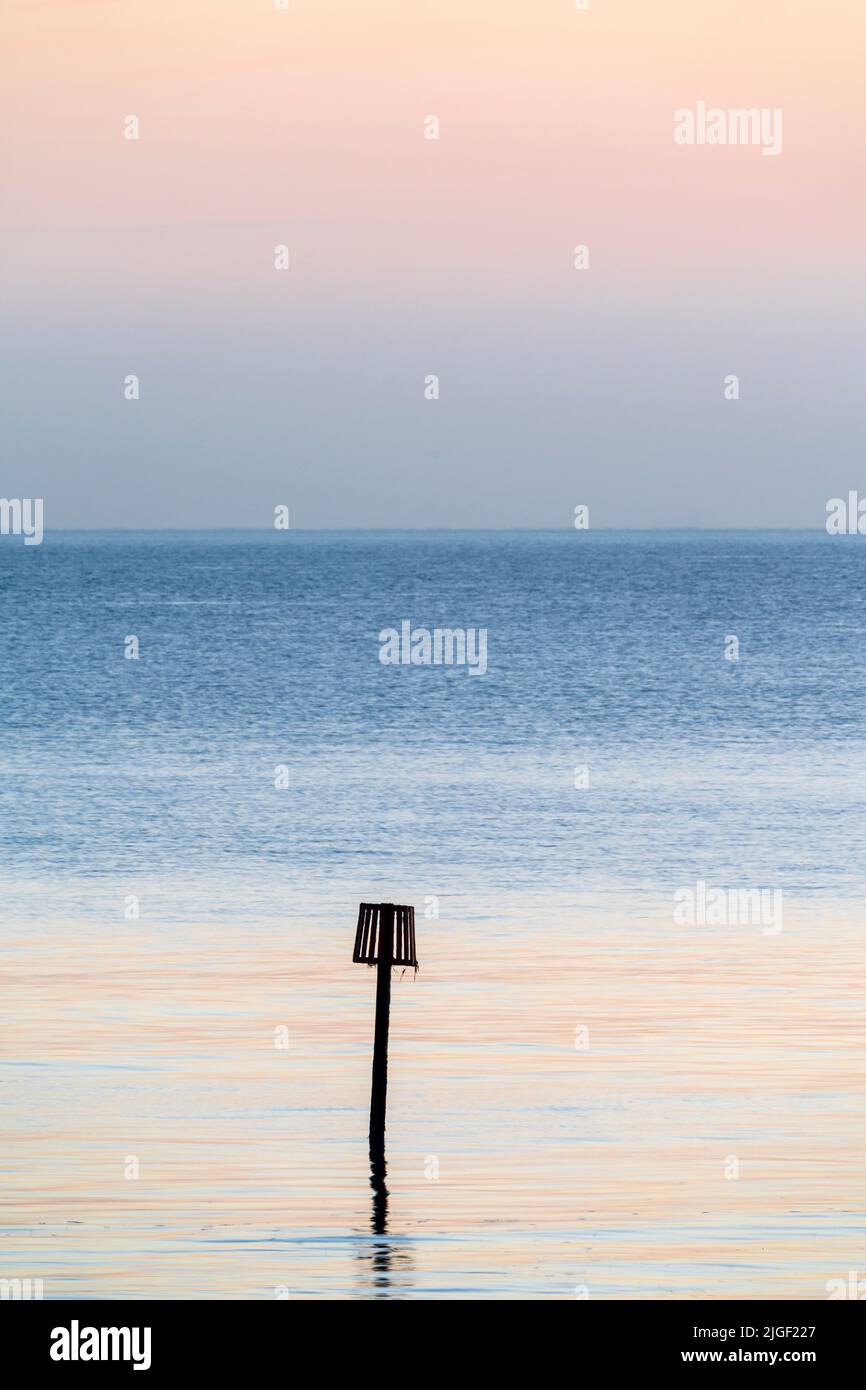 Sea post warning pole sticking out of a very calm sea off the shore at ...