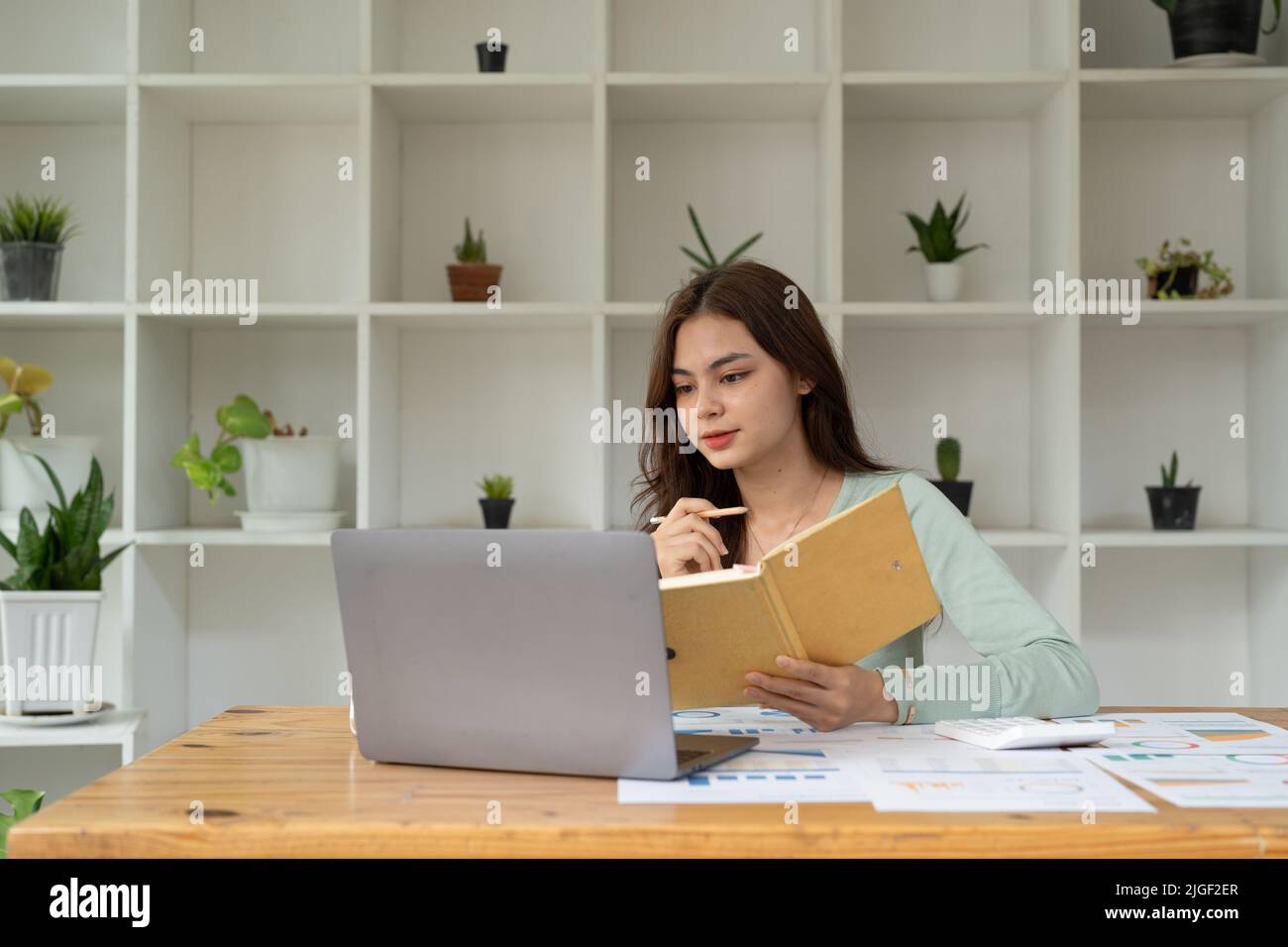 Concentrated female student busy studying using laptop make notes in ... Concentrated female student busy studying using laptop make notes in ...