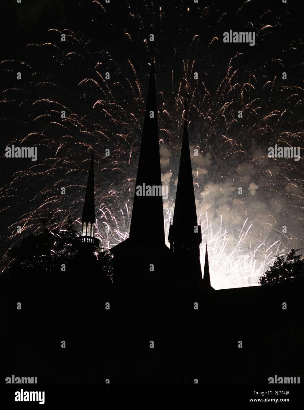 A vertical shot of exploding fireworks behind a tower silhouette Stock ...