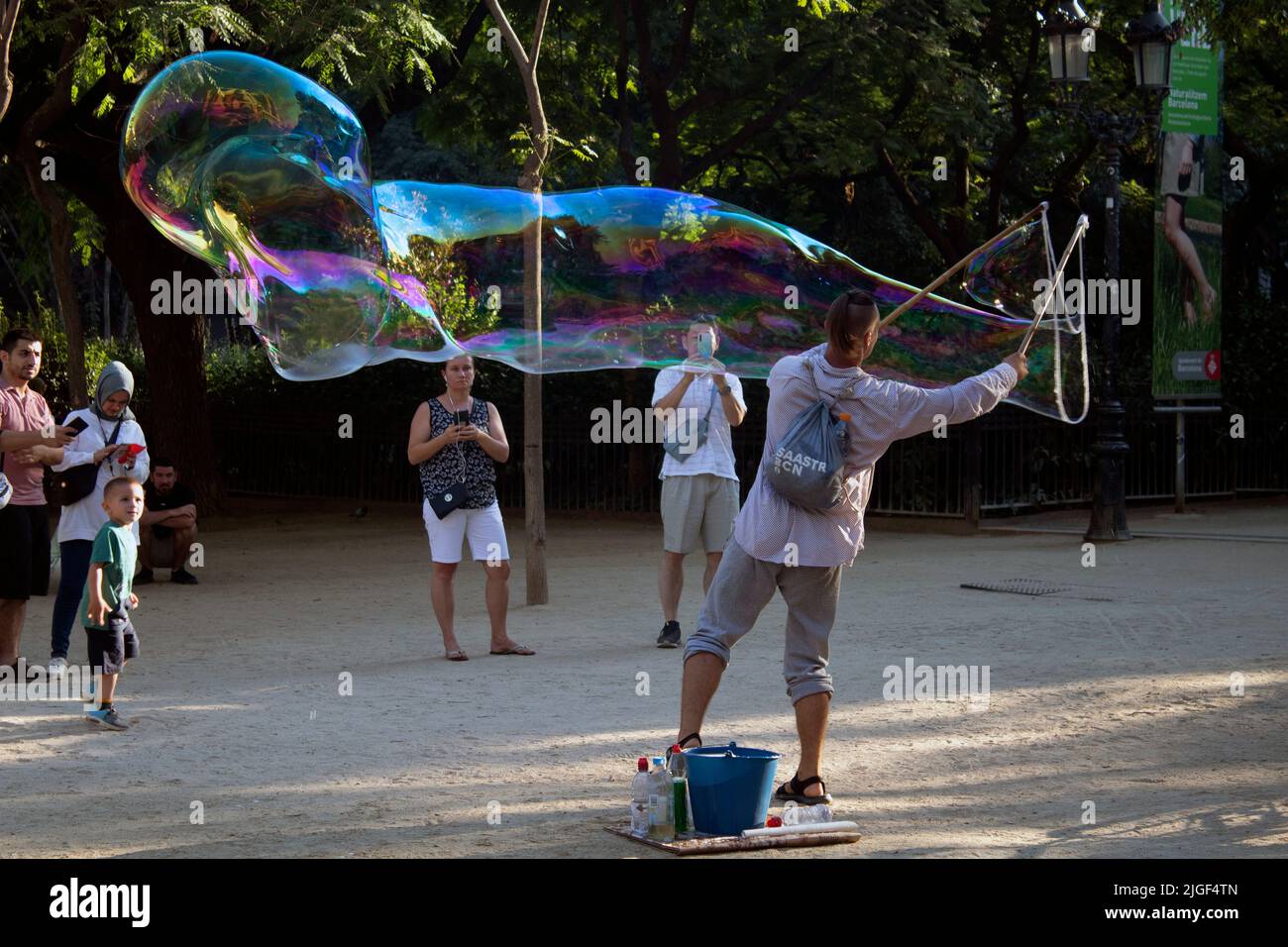 Man creating giant bubbles with a giant bubble wand in the Plaça de la ...