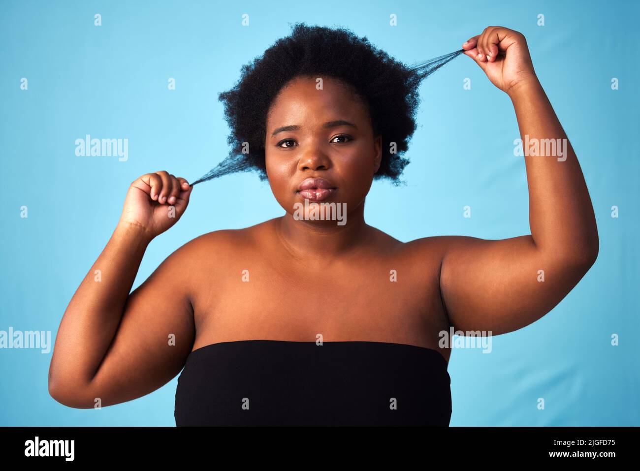 Let that fro grow. Studio shot of a beautiful young woman pulling ...