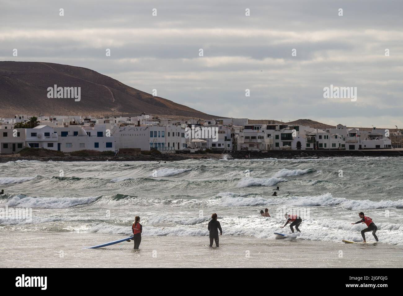 People practicing surf in Famara Beach, in the north west coast of the ...