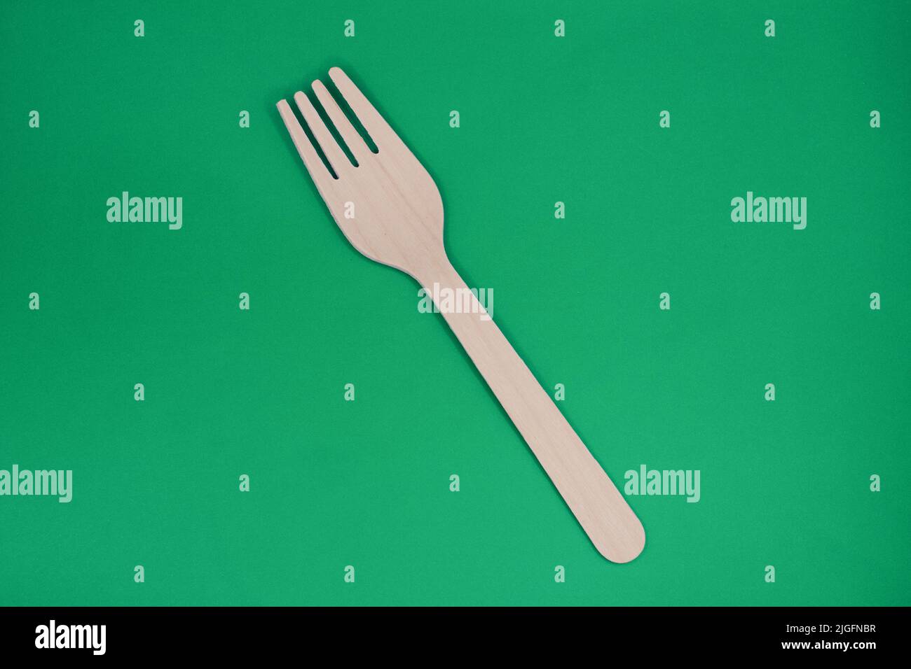 Wooden biodegradable fork in a green background concept of ecological ...