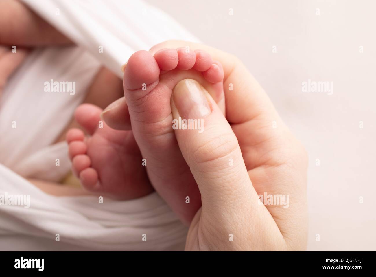 The palms of the father, the mother are holding the foot of the newborn ...