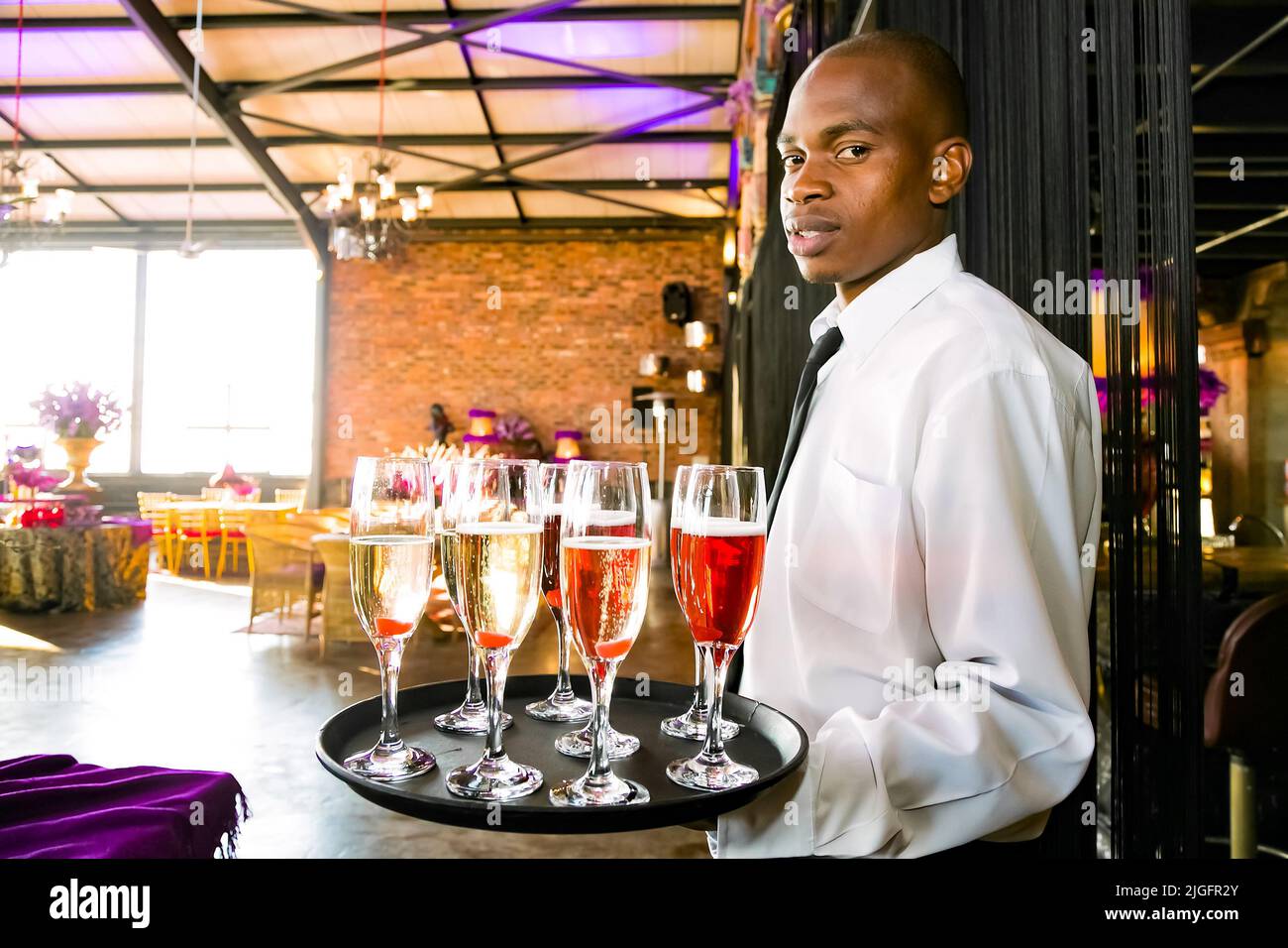 An African waiter holding tray of welcome drinks at event Stock Photo ...