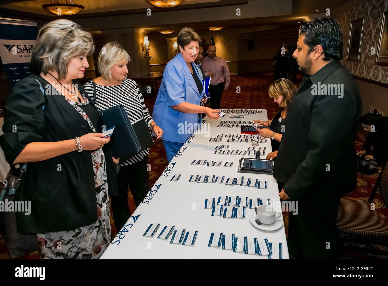 A group of delegates registering for a corporate event and picking up ...