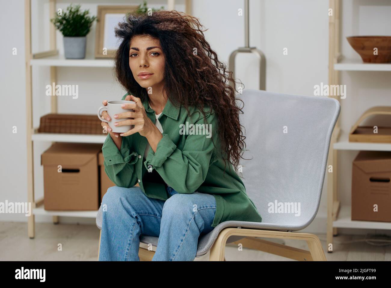 Frustrated tanned curly Latin lady troubled with problem with cup of ...