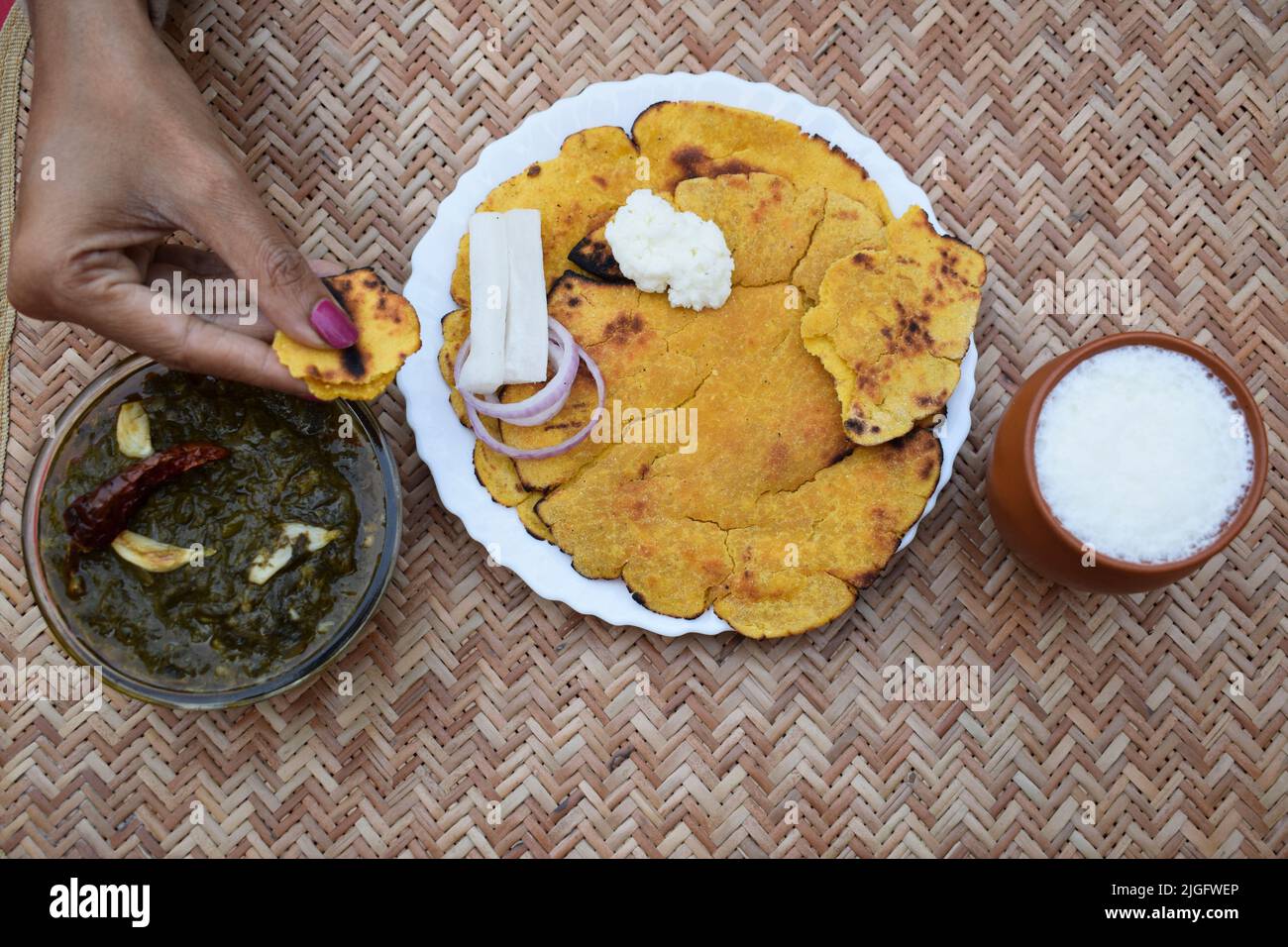 Person eating on table Indian popular dish makki di roti and Sarson da ...