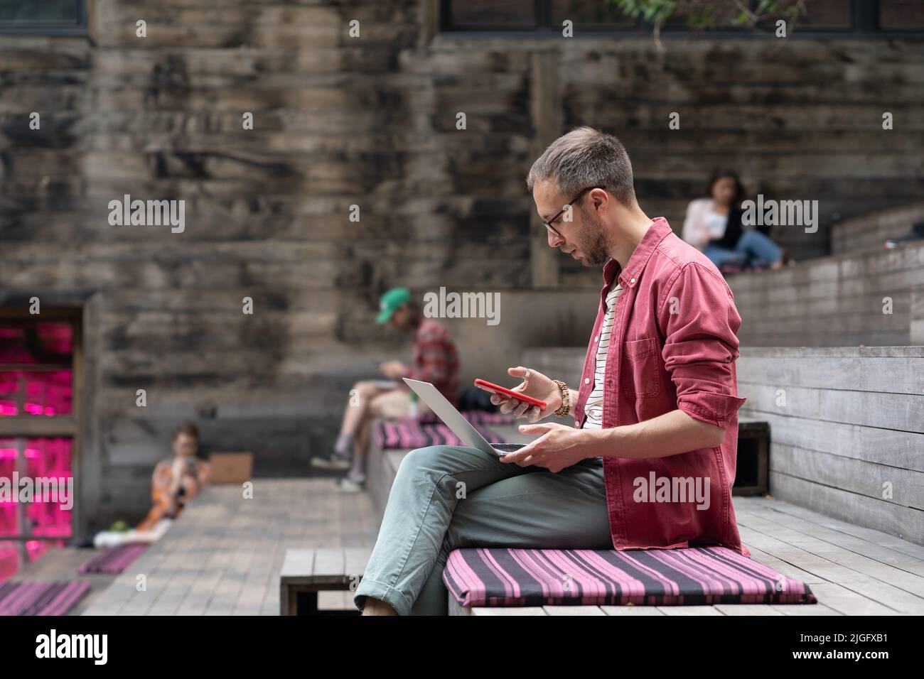 Focused ui ux designer looking at smartphone screen, distracted by his ...
