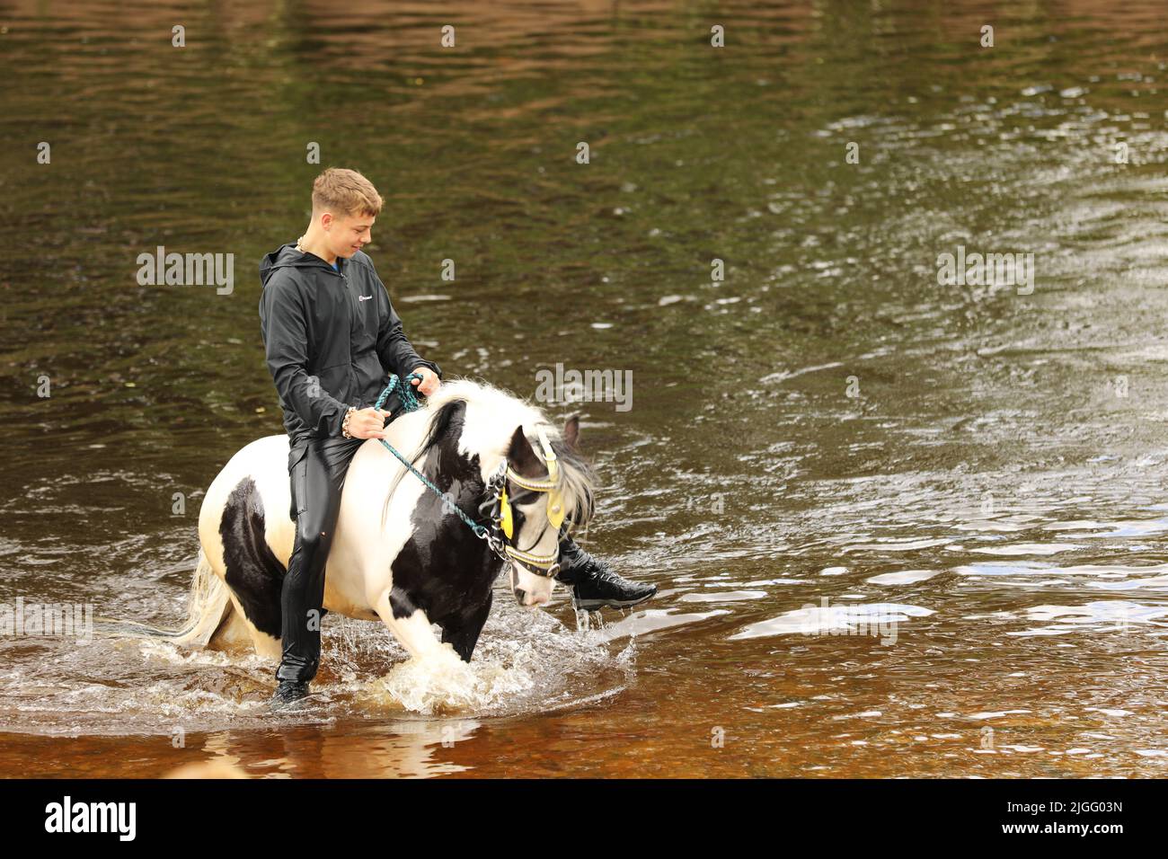 A teenage boy riding his horse in the River Eden, Appleby Horse Fair ...