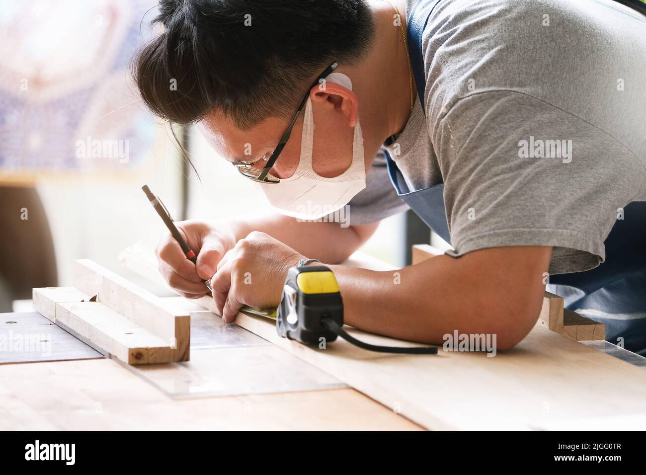 A carpenter measures the planks to assemble the parts and build a ...