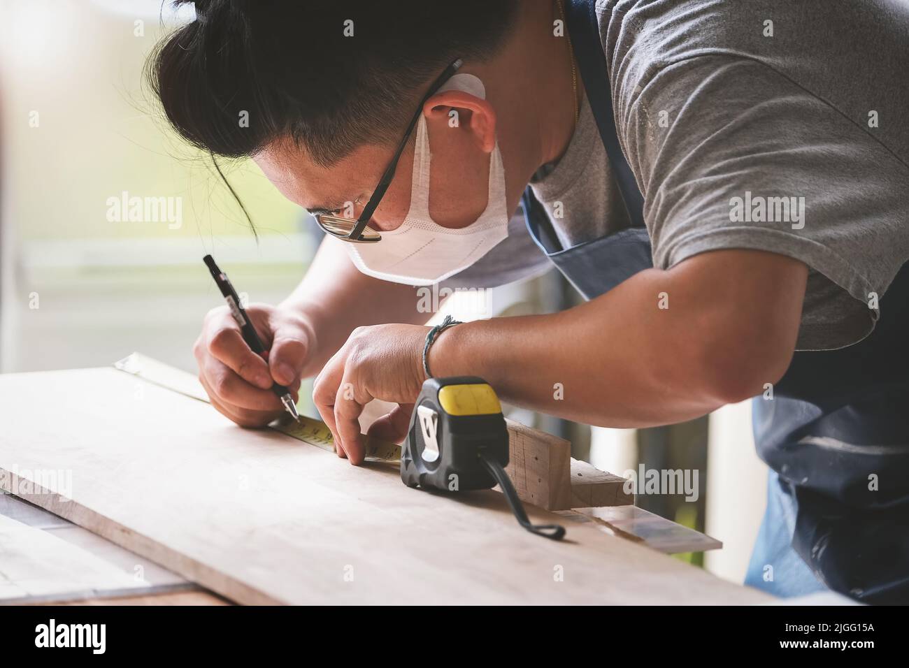 A carpenter measures the planks to assemble the parts and build a ...
