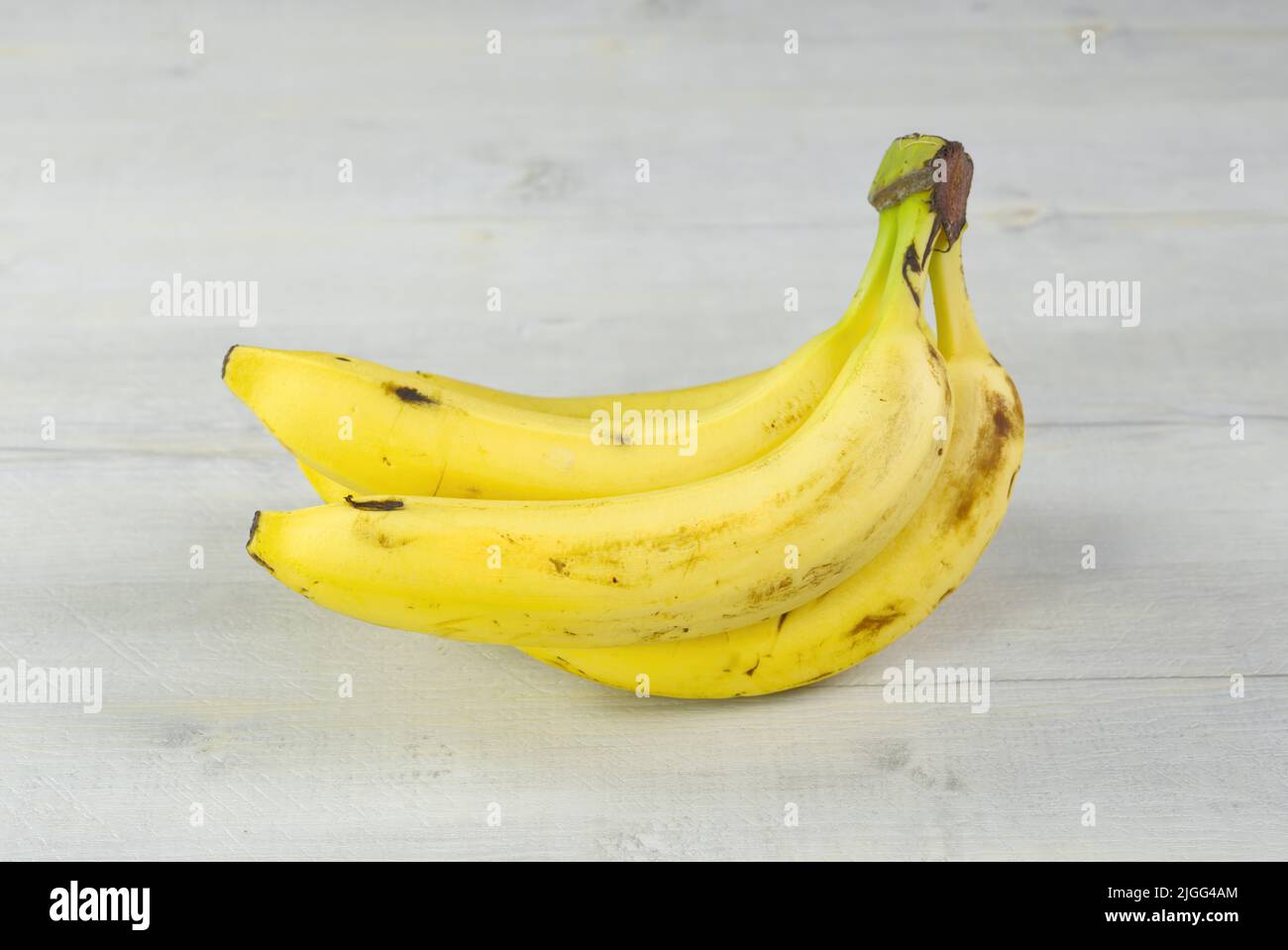 Banana bunch on a light wooden background Stock Photo - Alamy