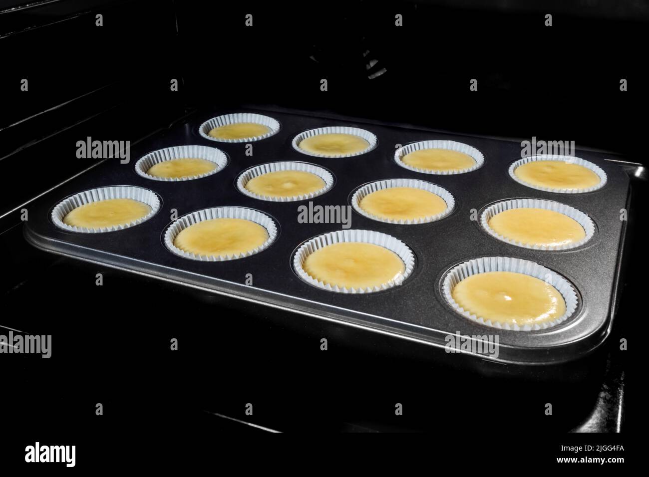 Uncooked homemade cupcakes, muffins in electric oven, black background ...