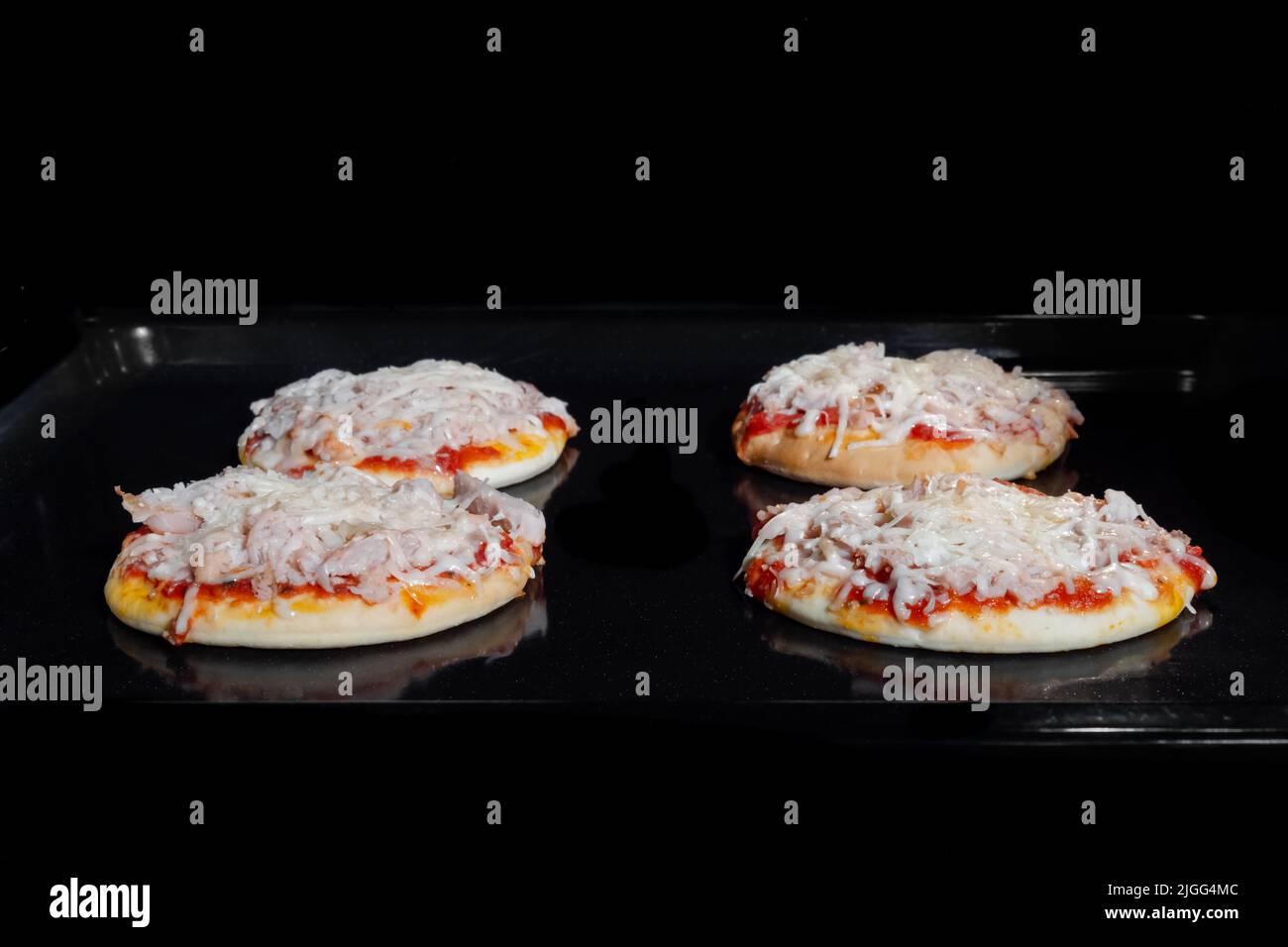 Four baked mini pizzas in electric oven at home: front view Stock Photo - Alamy