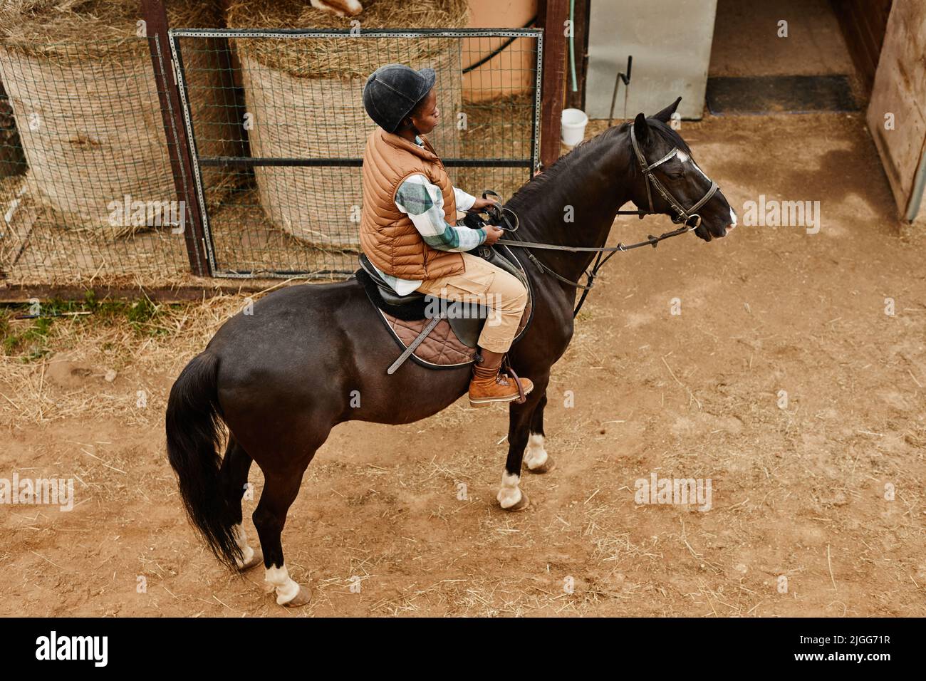 High angle portrait of young woman riding horse in ranch and leading to ...