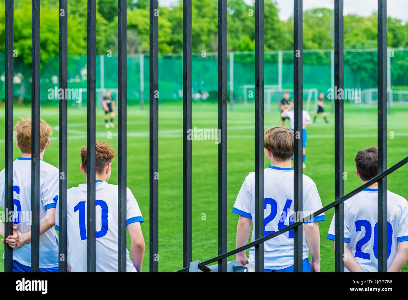 Young Football Players standing on edge of football field, back view ...