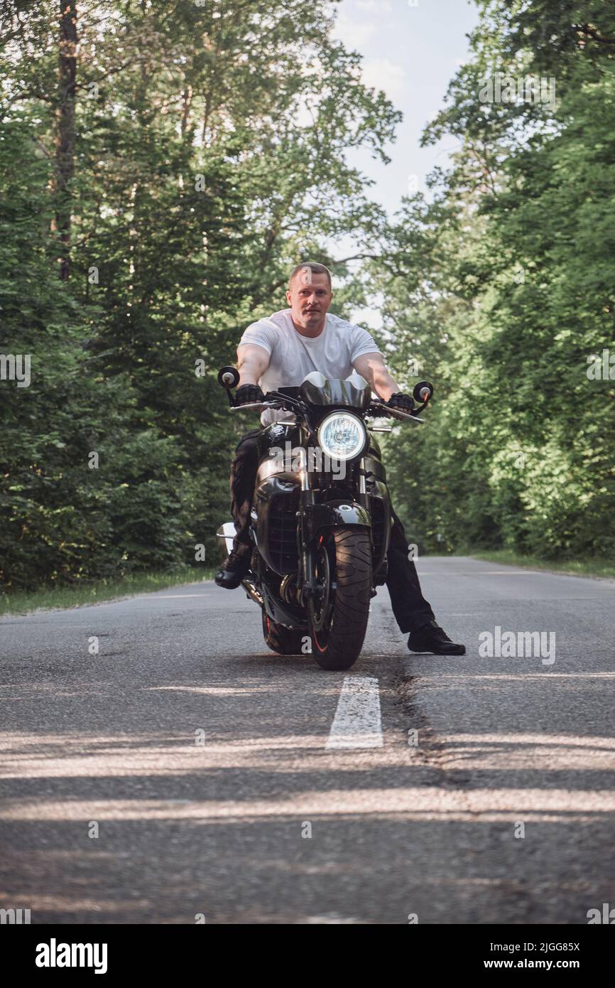 Young male biker travels on a motorcycle alone, on an asphalt road in ...