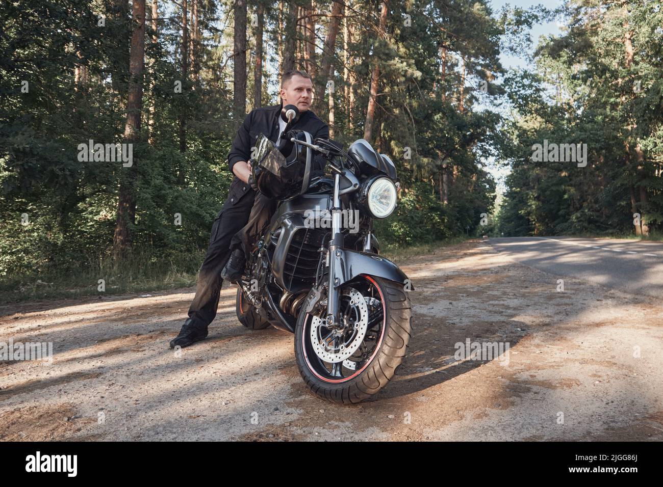 Young male biker travels on a motorcycle alone, stopped on the side of ...