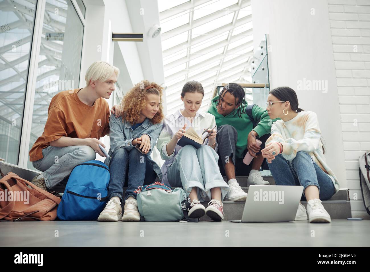 Clever teenage students of college or highschool looking through ...