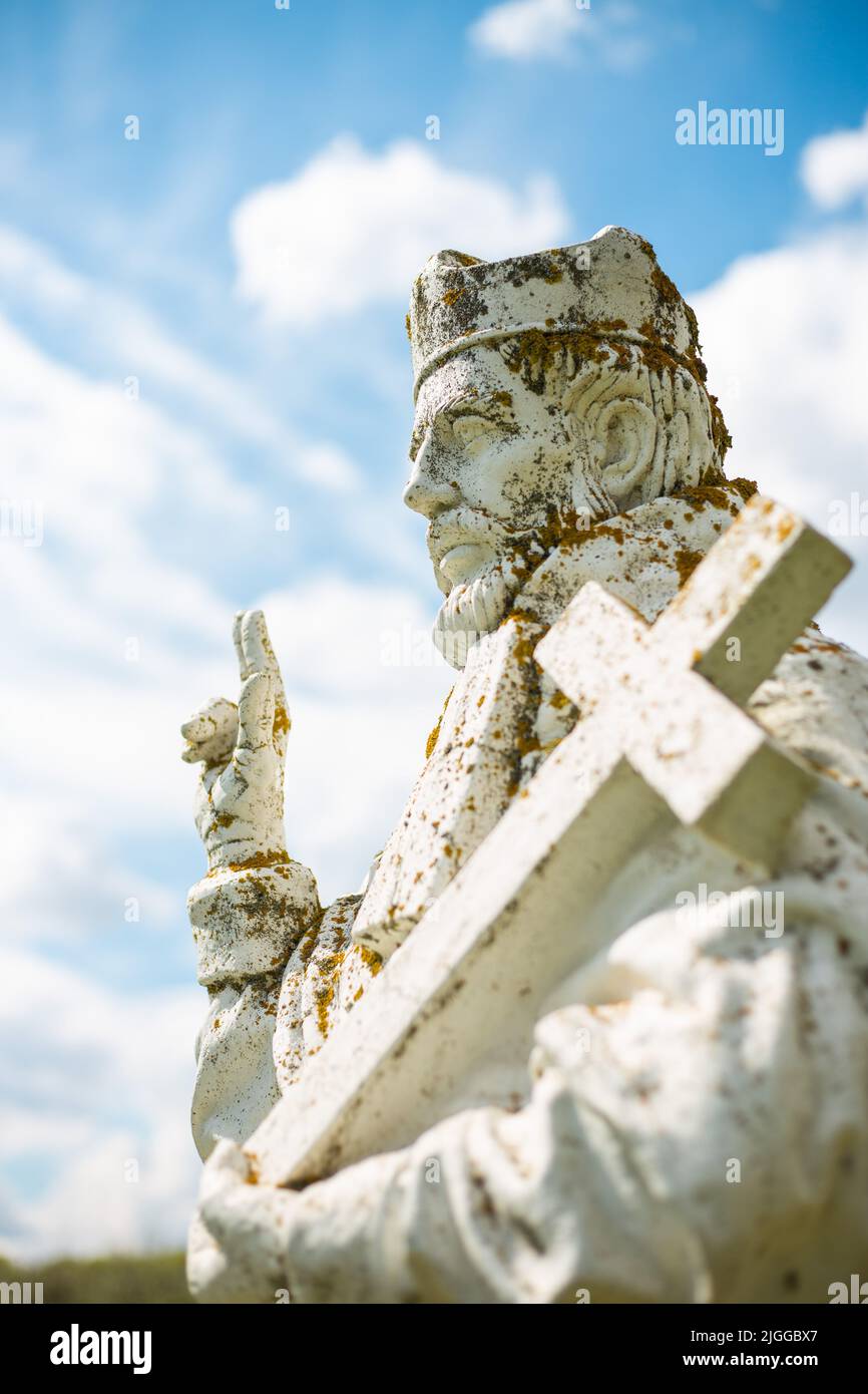 A vertical shot of an old white statue of a priest in Opusztaszer ...
