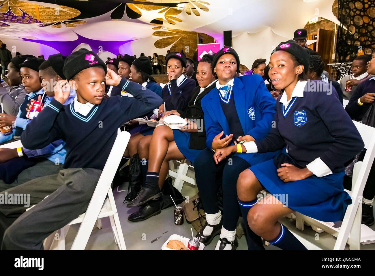 A group of young African pupils attending an event in their school hall ...