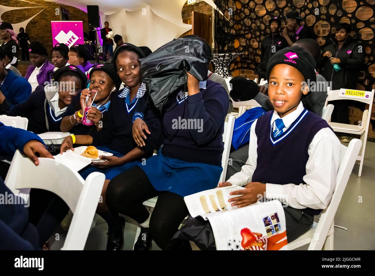 A group of young African pupils attending an event in their school hall ...