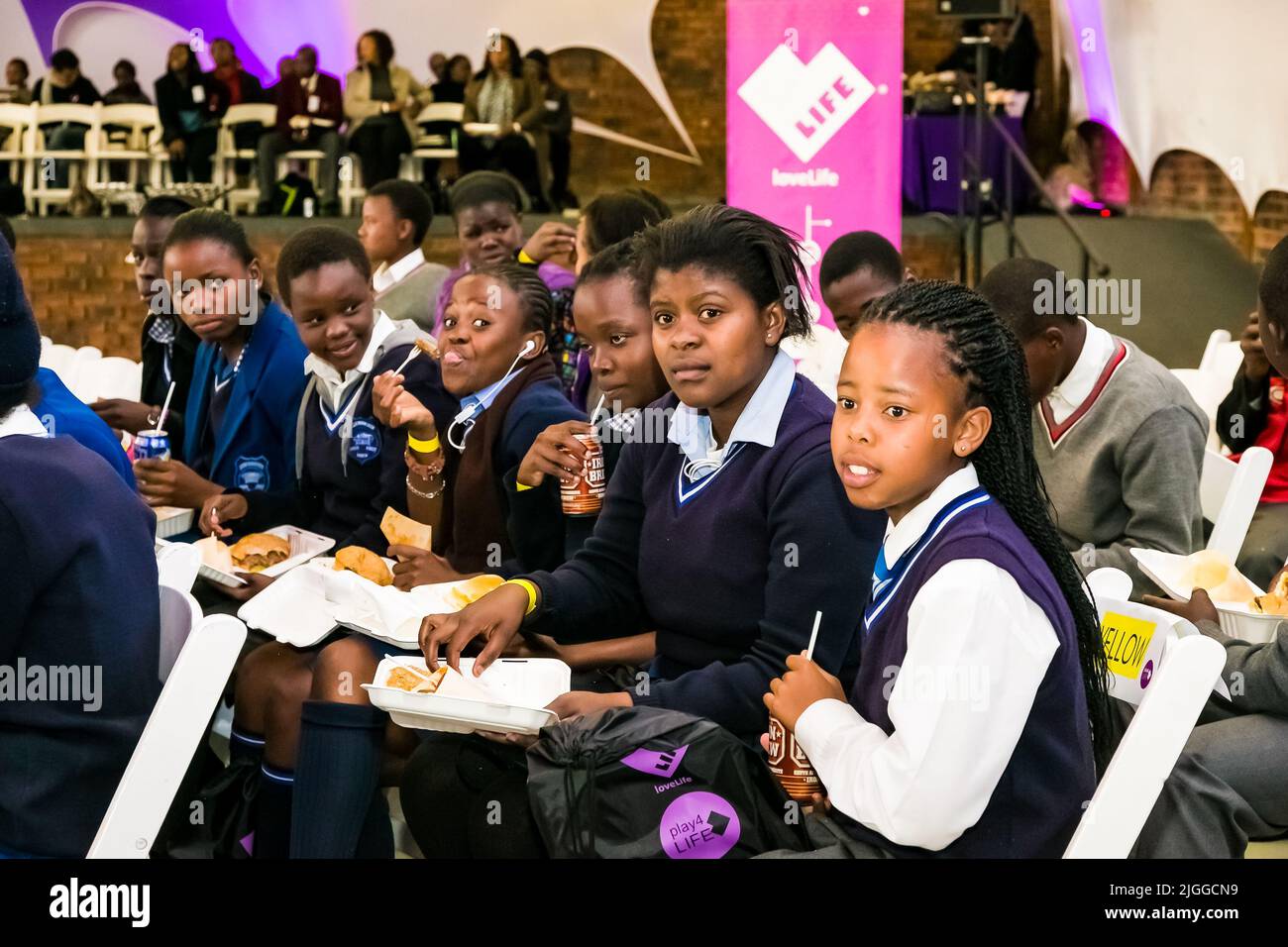A group of young African pupils attending an event in their school hall ...