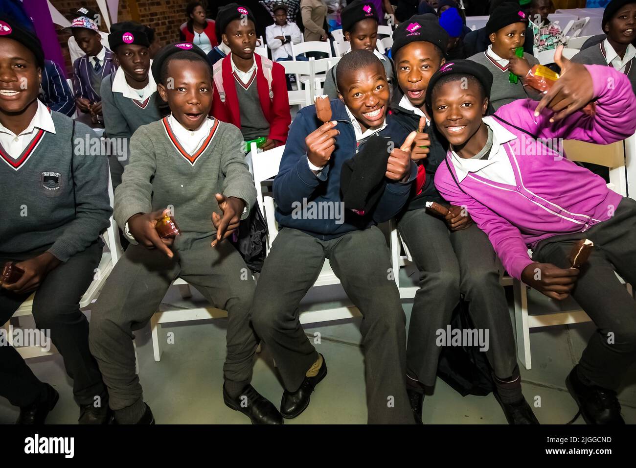 A group of young African pupils attending an event in their school hall ...