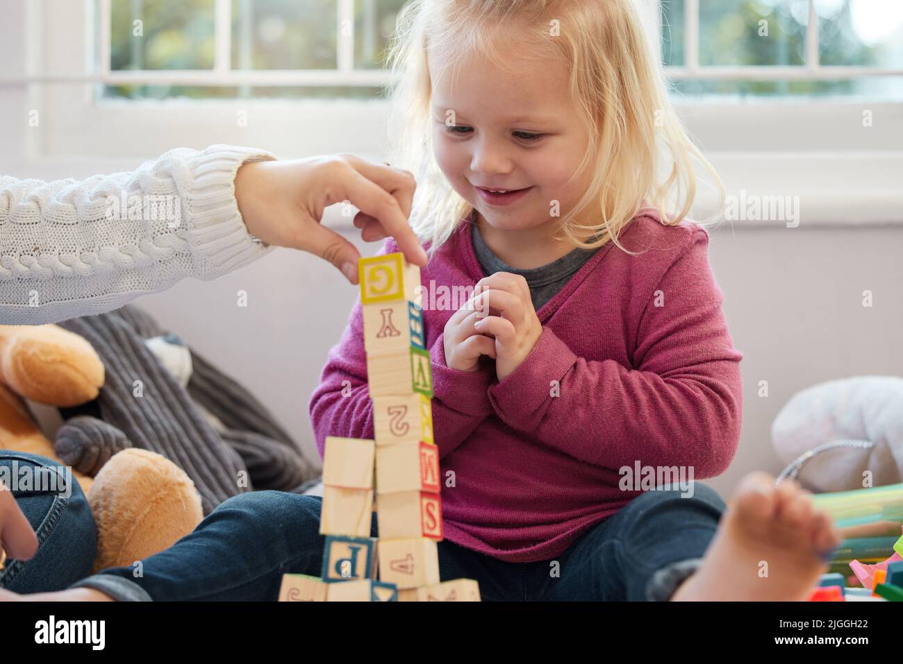 Lets add one more. a little girl stacking blocks with her mother at ...