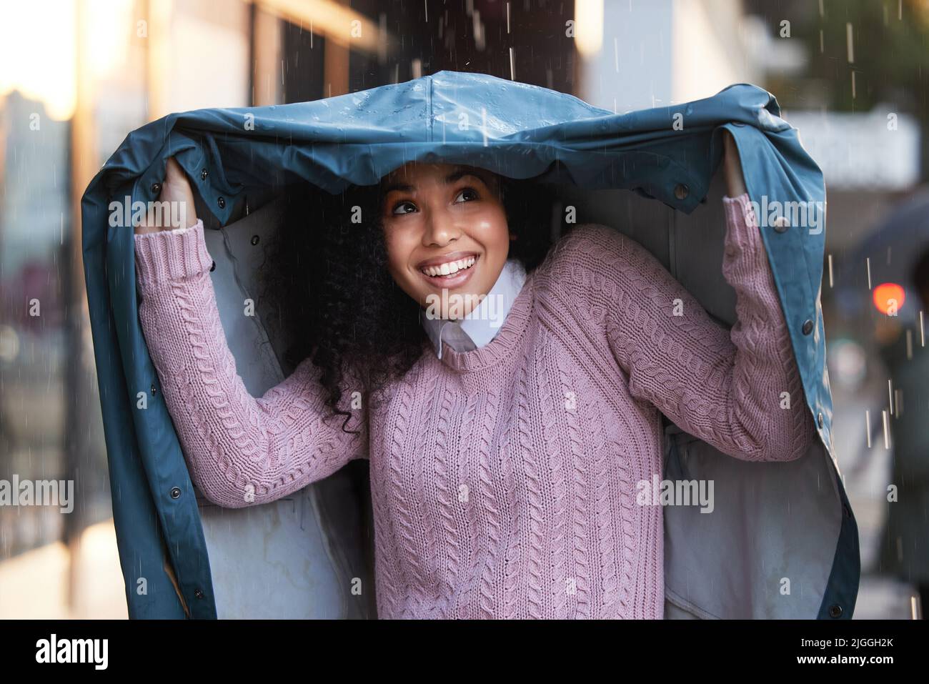 Its really pouring down today. a young woman covering herself with a ...