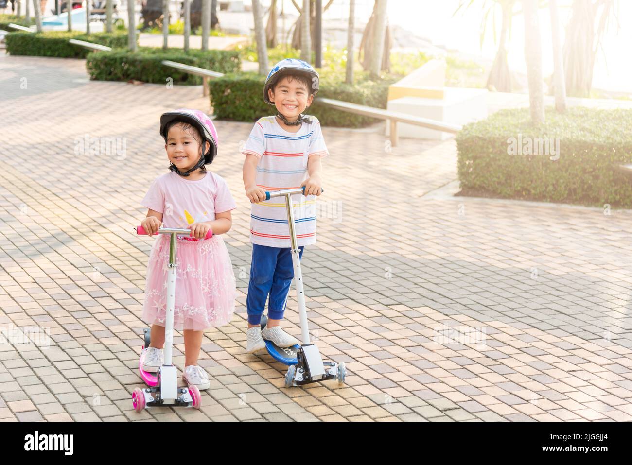 Child riding scooter. Happy Asian little kid boy and girl wear safe ...