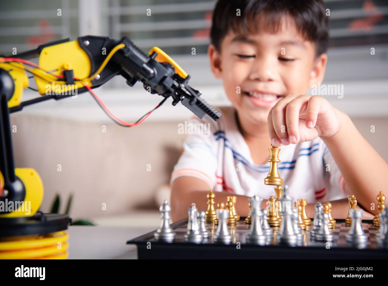 Asian little boy is playing chess with robot machine arm, STEM ...