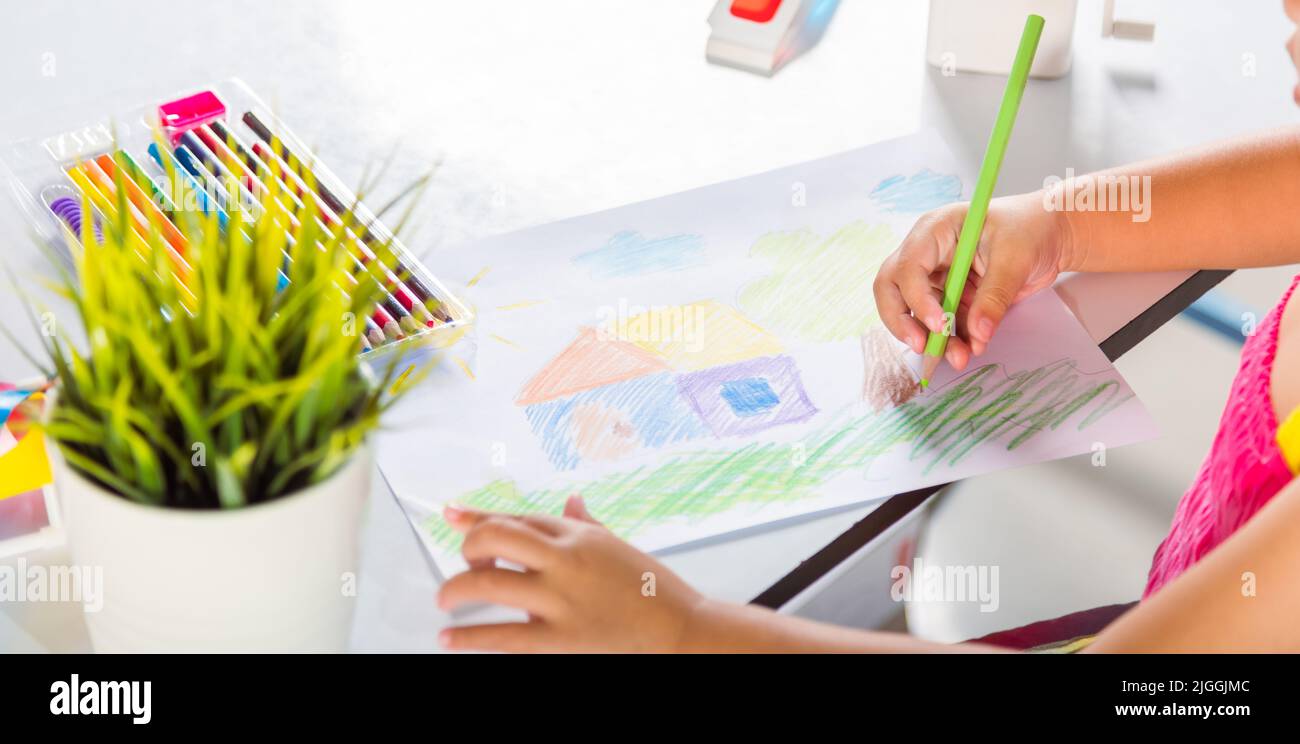 Asian cute kid preschooler sit on table smile she draw country house ...
