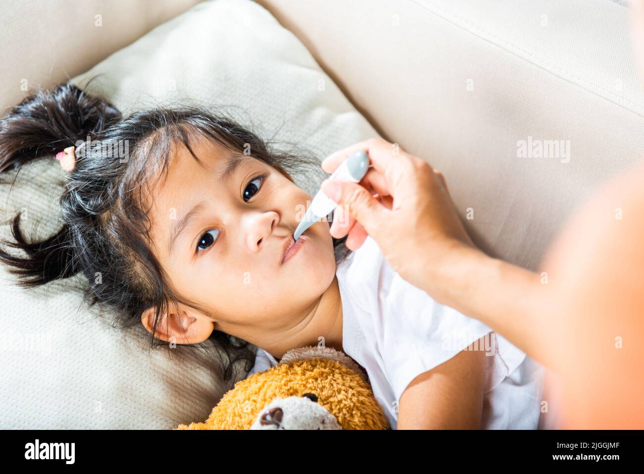 Sick kid. Mother parent checking temperature of her sick daughter with digital thermometer in ...