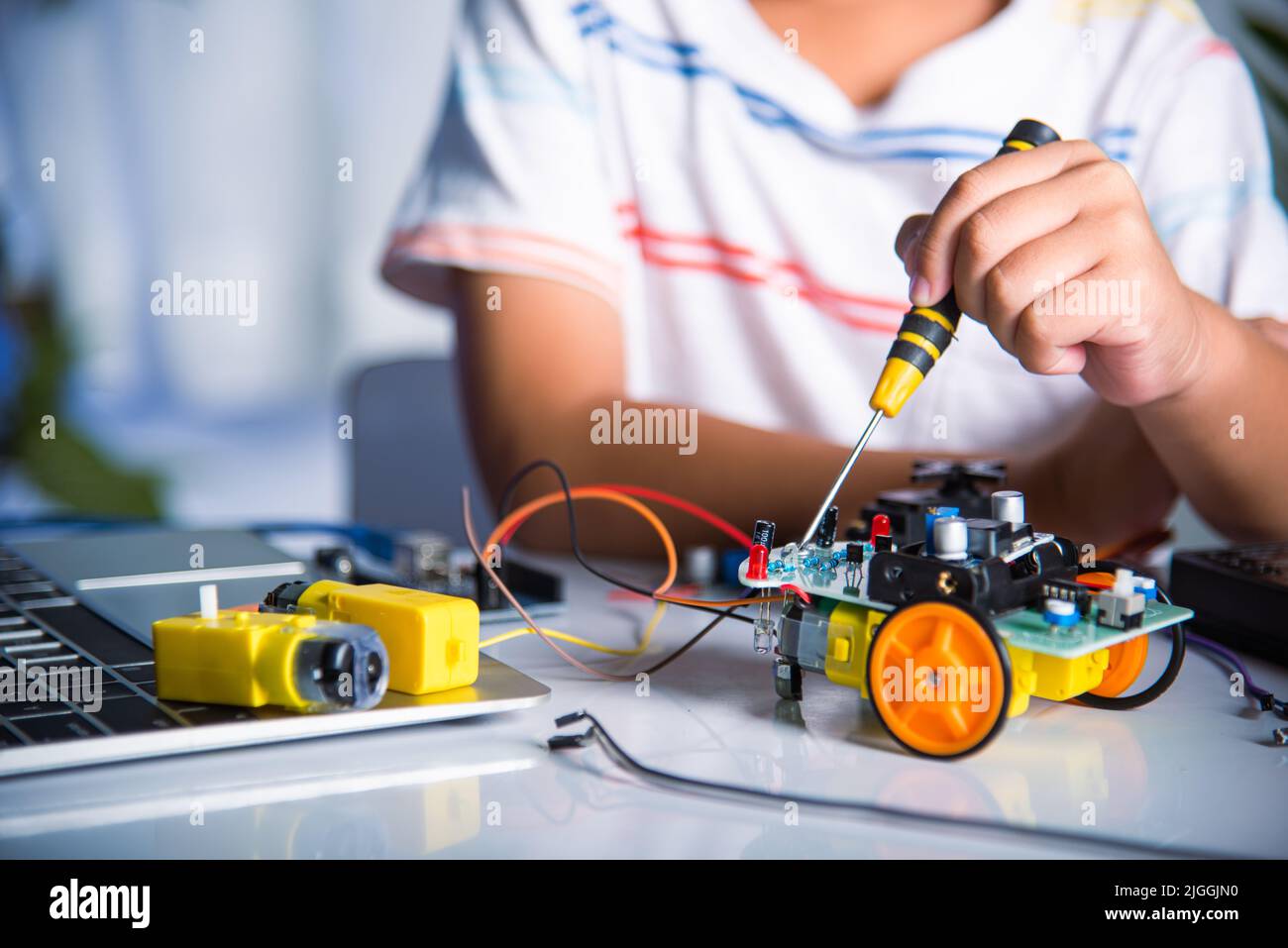 Little child tighten the nut with a screwdriver to assemble car toy ...