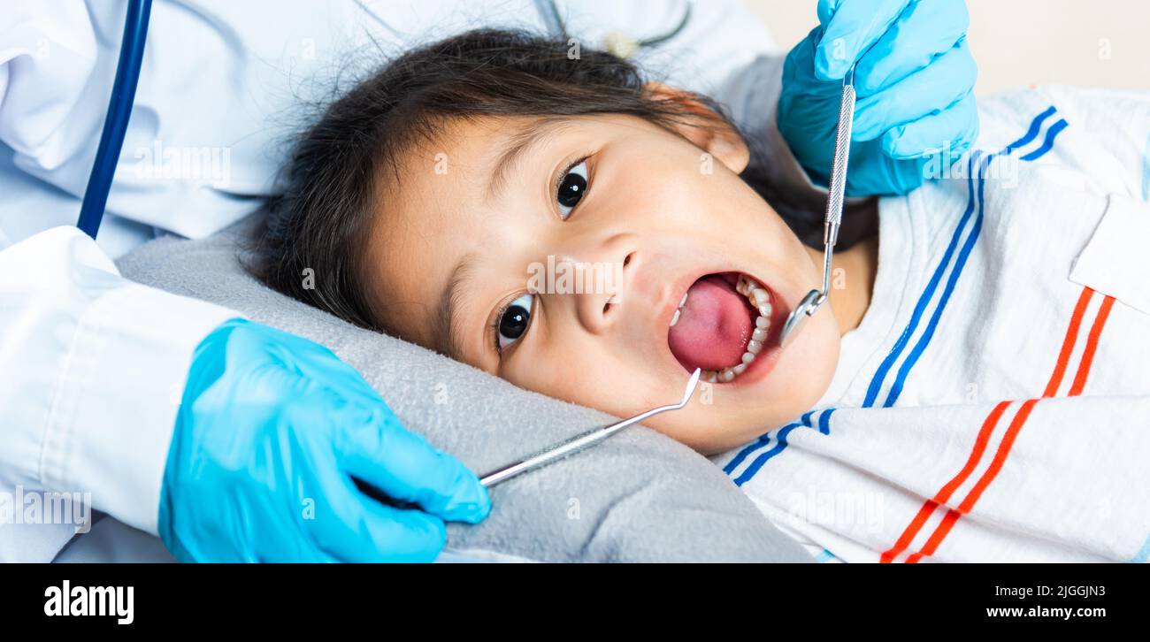 Dental kid health examination. Asian dentist making examination procedure for cute little girl ...