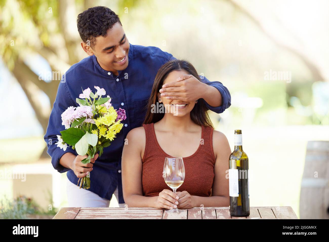 Guess who. a handsome young man surprising his girlfriend with flowers ...