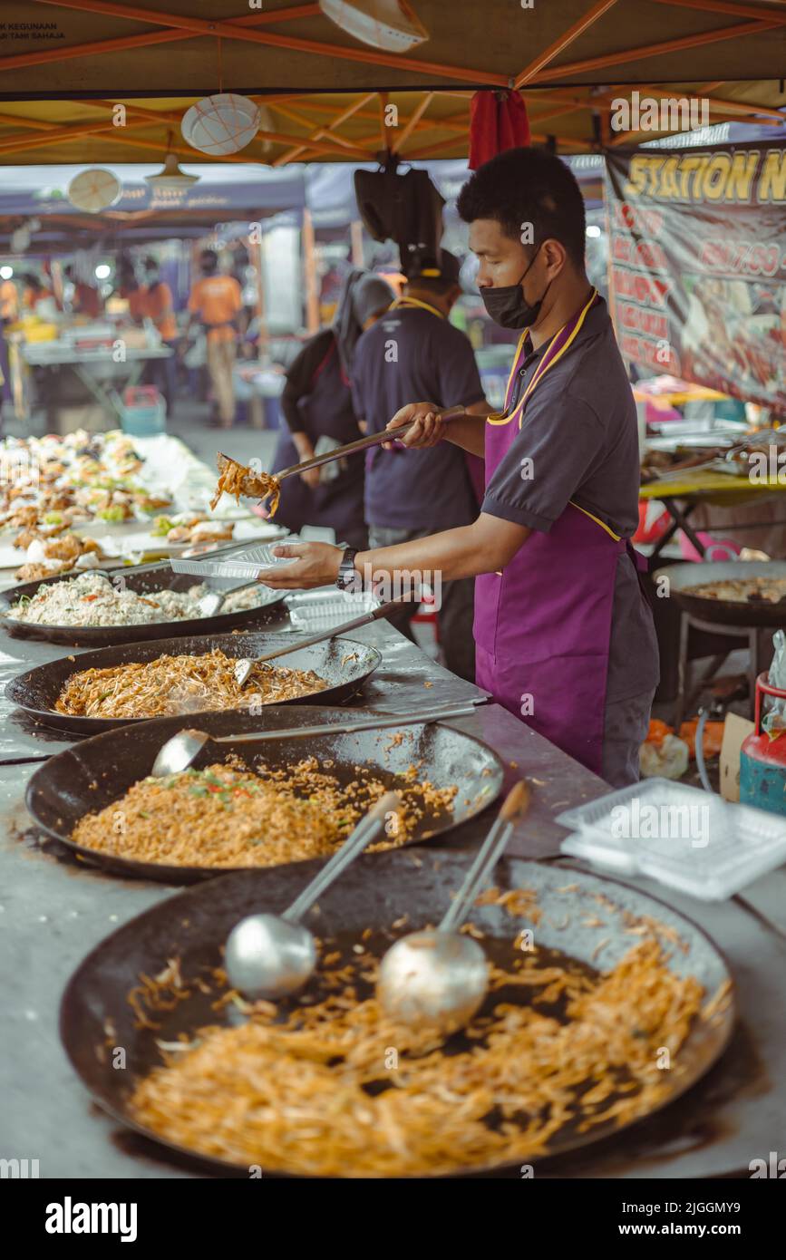 Kuala Lumpur, Malaysia - June 21, 2022: A man preparing fried noodles ...