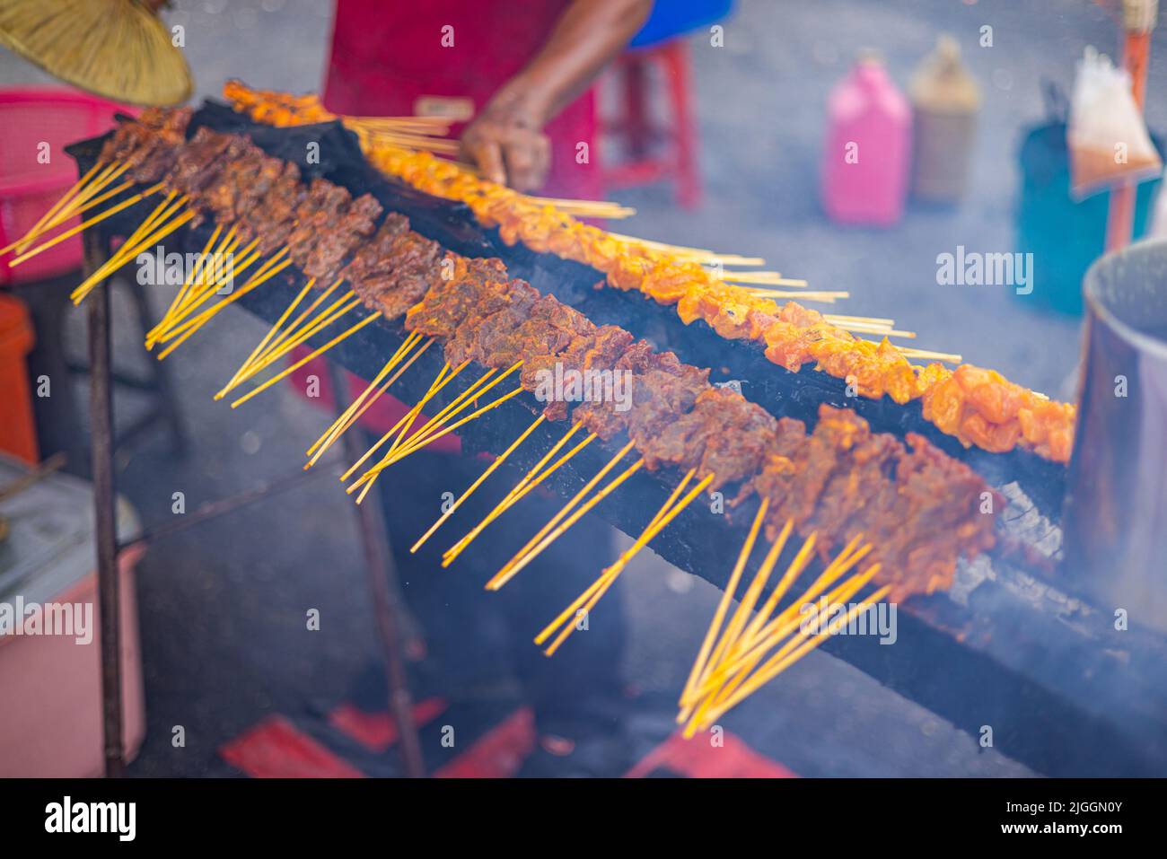 A grill rack on an open fire With satay or sate sticks. Traditional ...