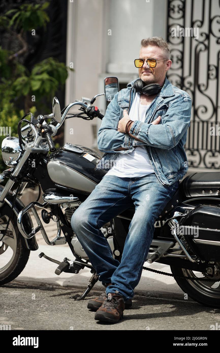 Portrait of confident mature man in jeans and demin jacket leaning on ...