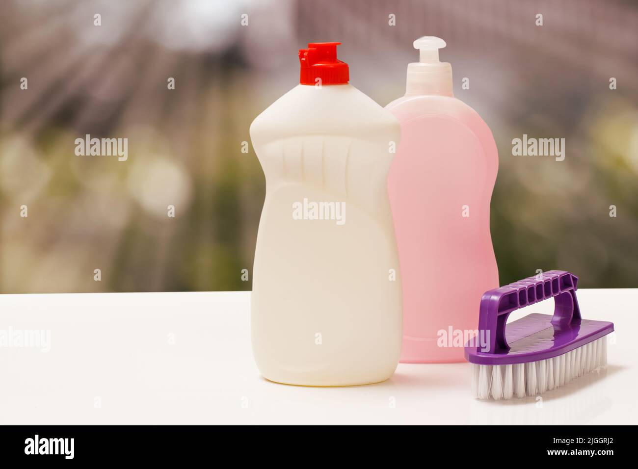 Bottles of washing liquid, a brush on the blurred background with sun ...