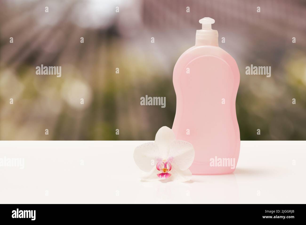 Bottle of dishwashing liquid and an orchid flower on the blurred ...